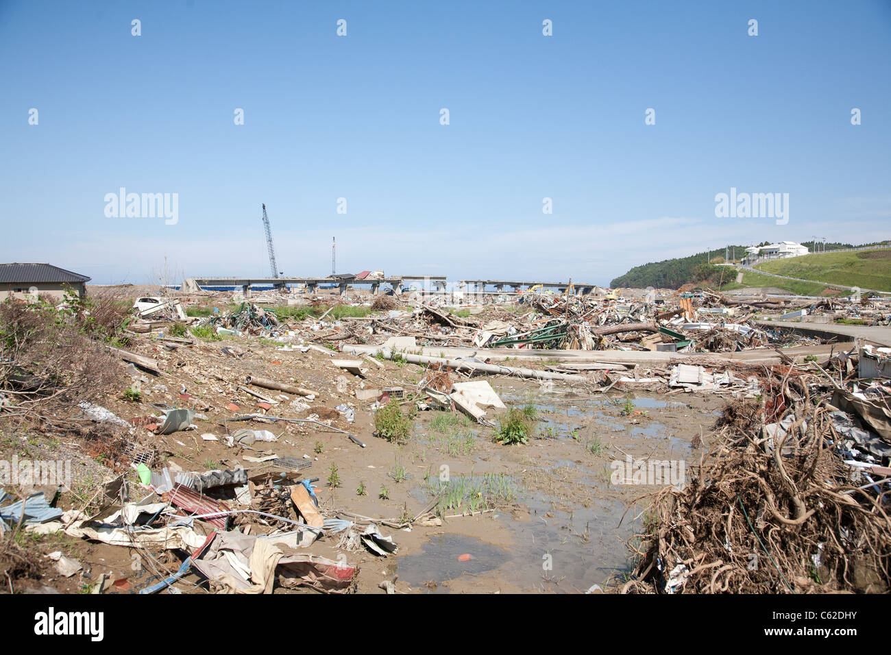 A damaged railroad bridge is in the distance with a debris field in the ...