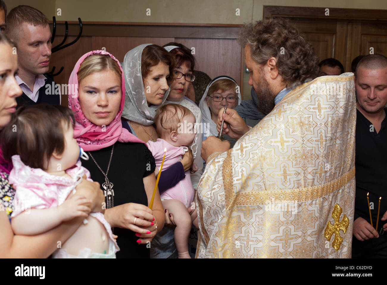 Baby baptism in Russian orthodox church. Priest christening the little child. Godmother holding ...