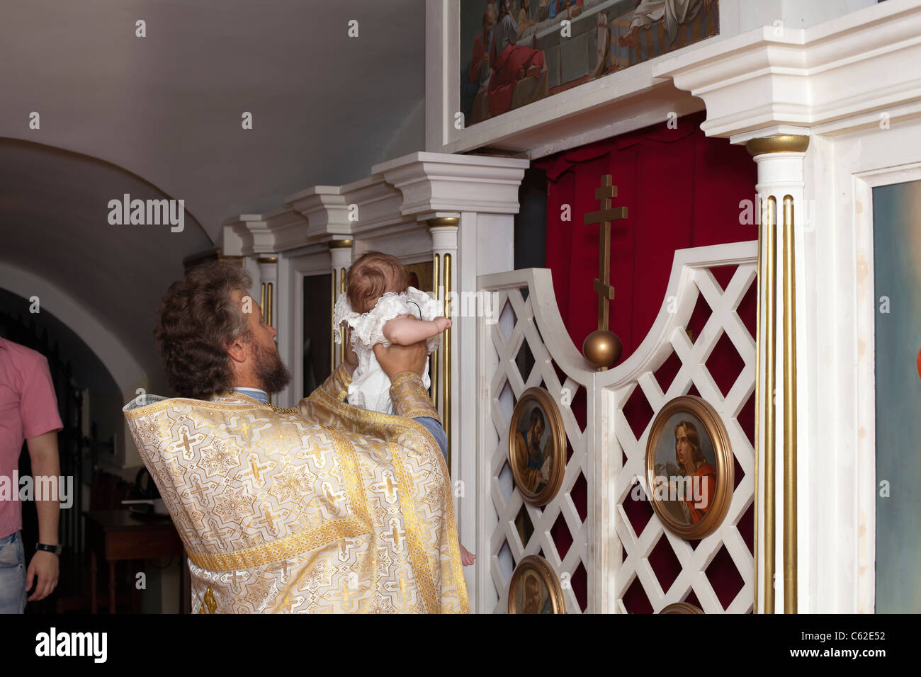 Baby baptism in Russian orthodox church. Priest christening the little child. Godmother holding ...