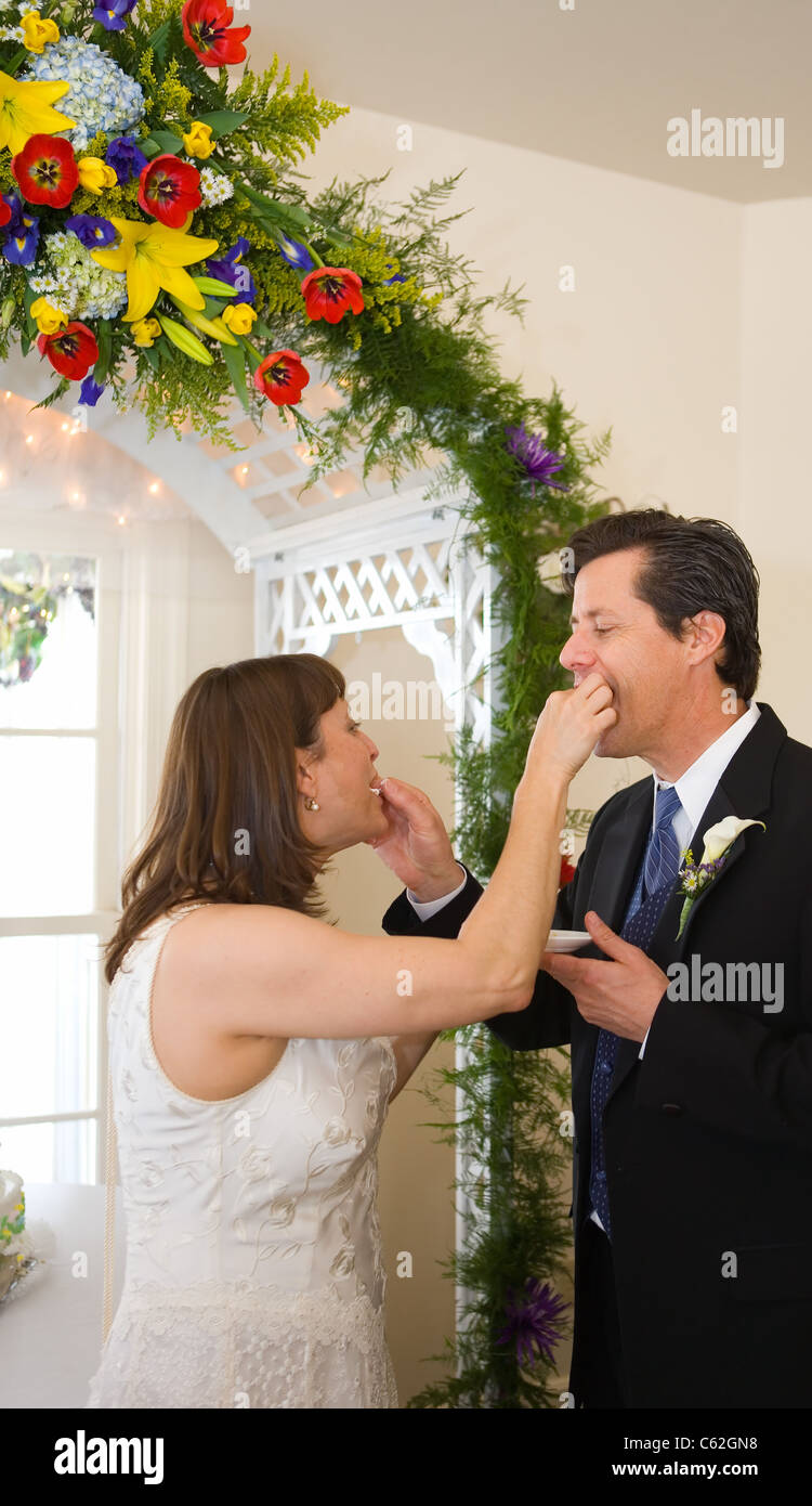 A bride and groom serve each other cake after the ceremonial cutting ...