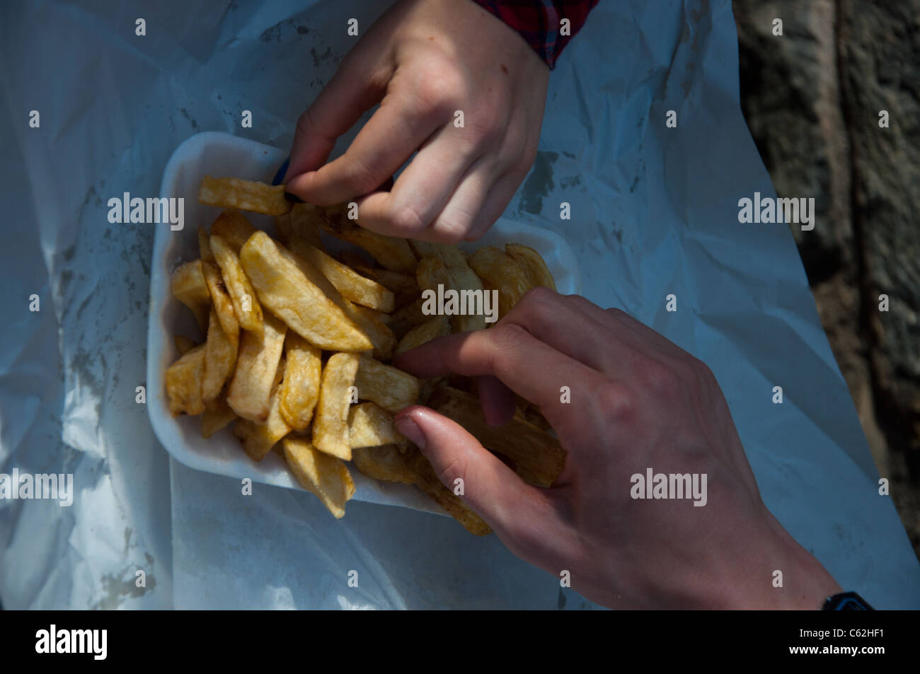 eating chips out of the paper on the street Stock Photo - Alamy