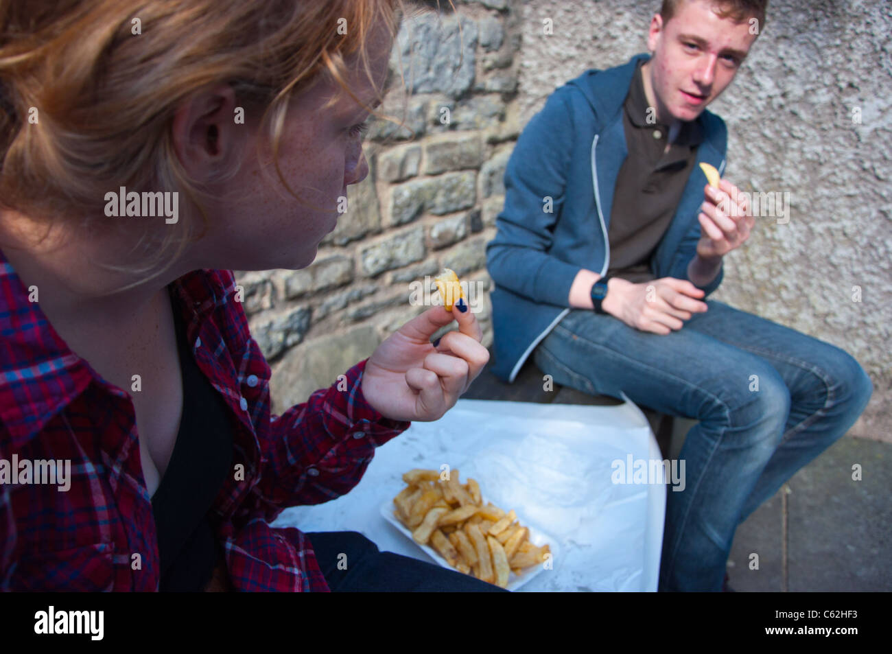 Teenagers boy and girl eating chips on the street Stock Photo - Alamy