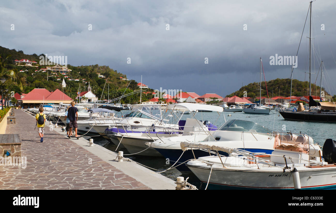 Children pass boats at the waterfront in Gustavia in St. Barts, with ...