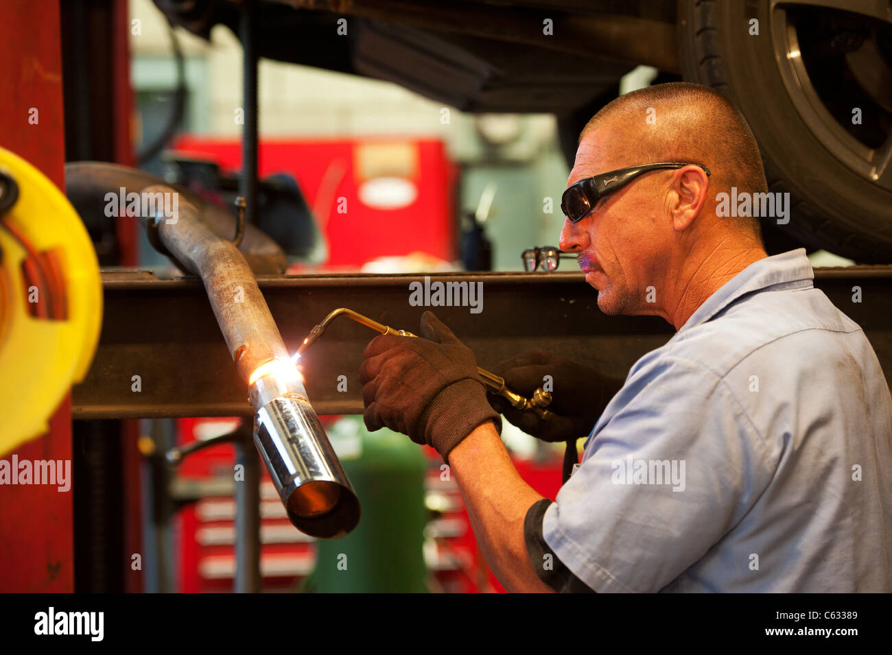 A Mechanic cuts a muffler pipe Stock Photo - Alamy