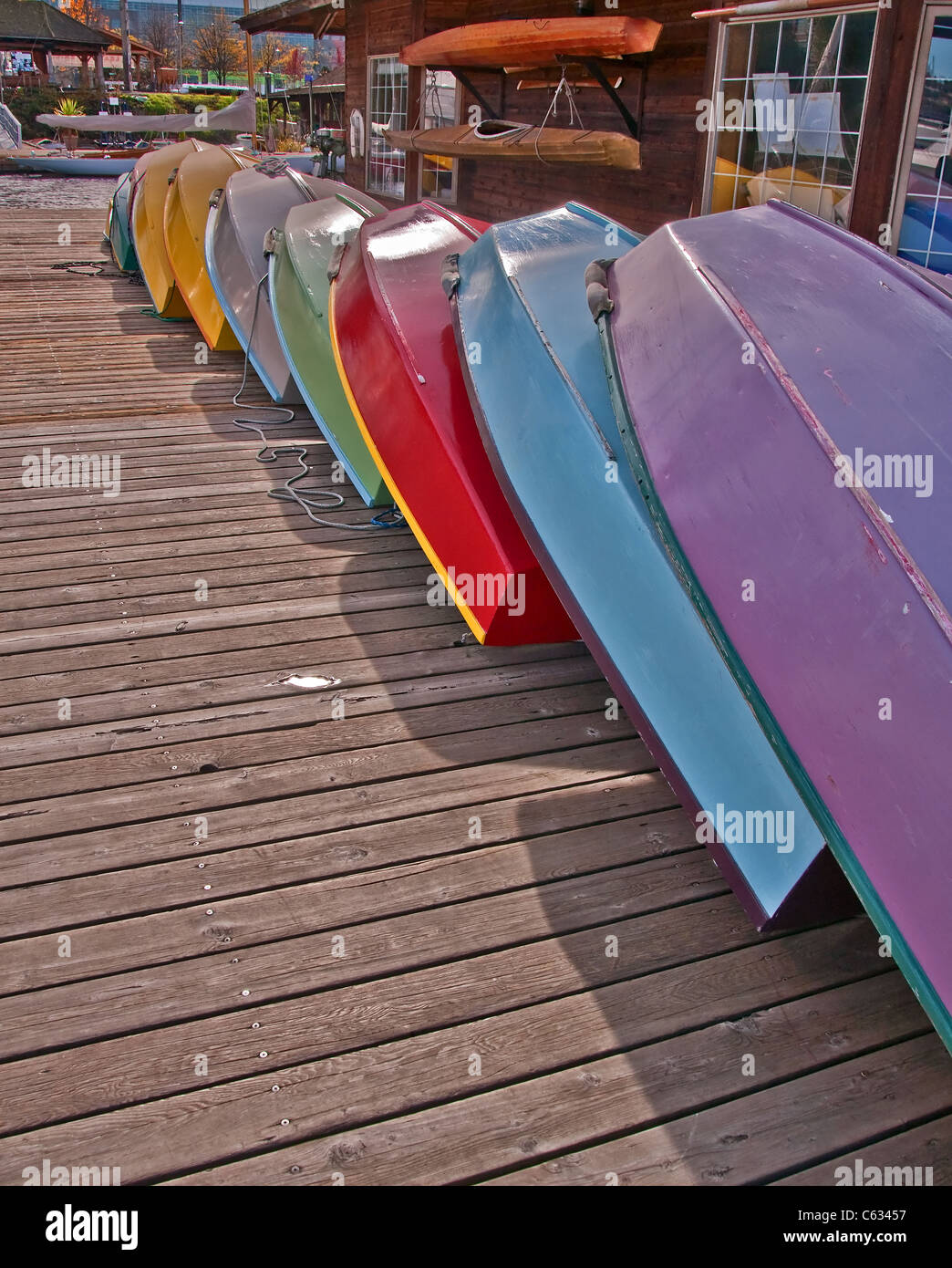 This vertical stock image shows a row of colorful rowboats with the ...