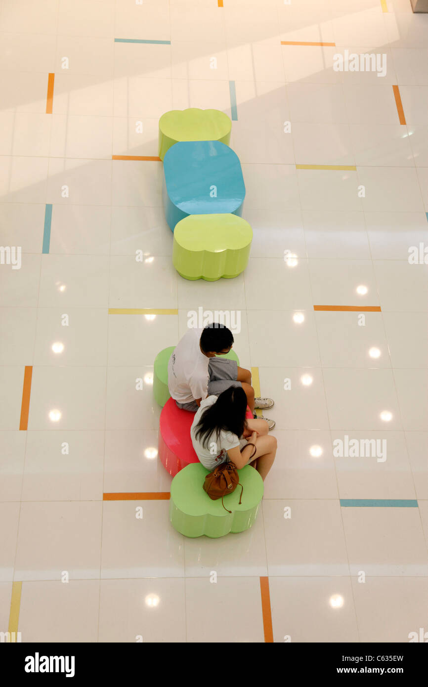 People sitting on seats resting in a shopping mall in Hong Kong, China ...