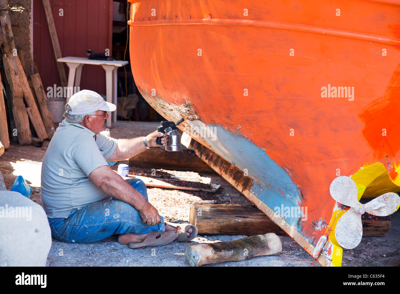 Santorini, Greek Island, Greece, man repairing hull of his fishing boat ...