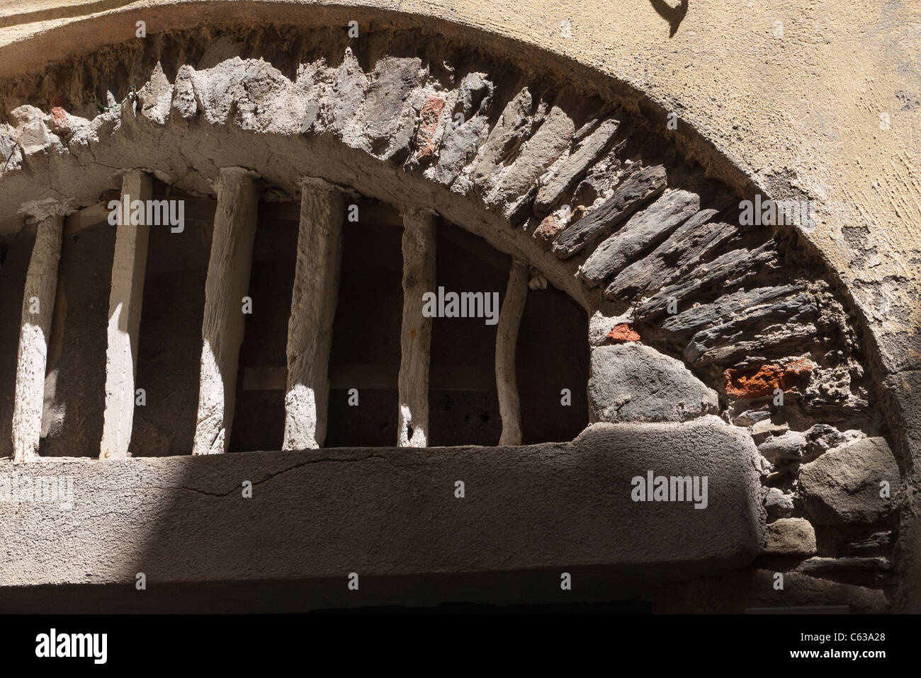A close up detail of a very old stone arch with wooden vertical bars ...