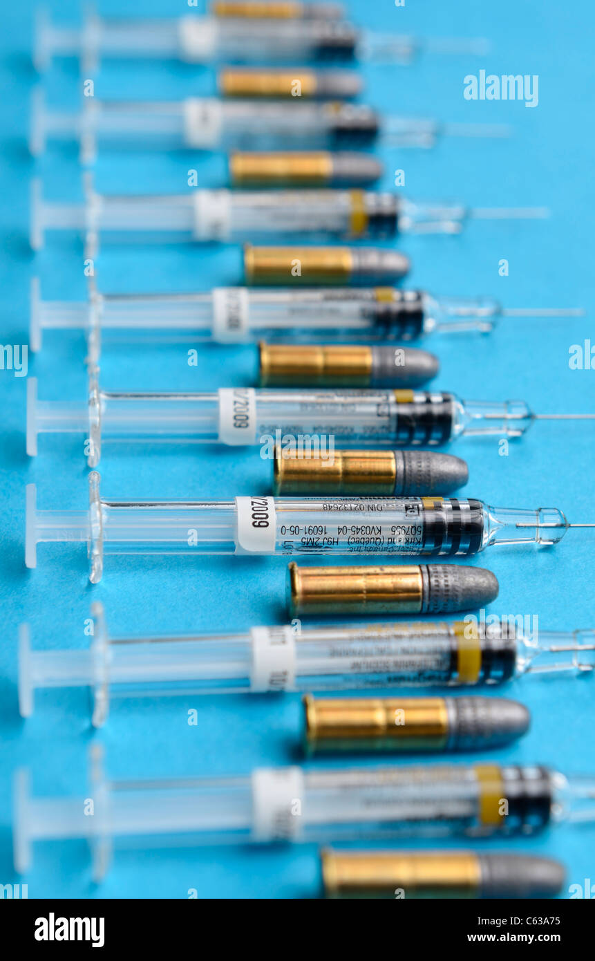 Row of hypodermic syringes alternating with bullets on a blue ...