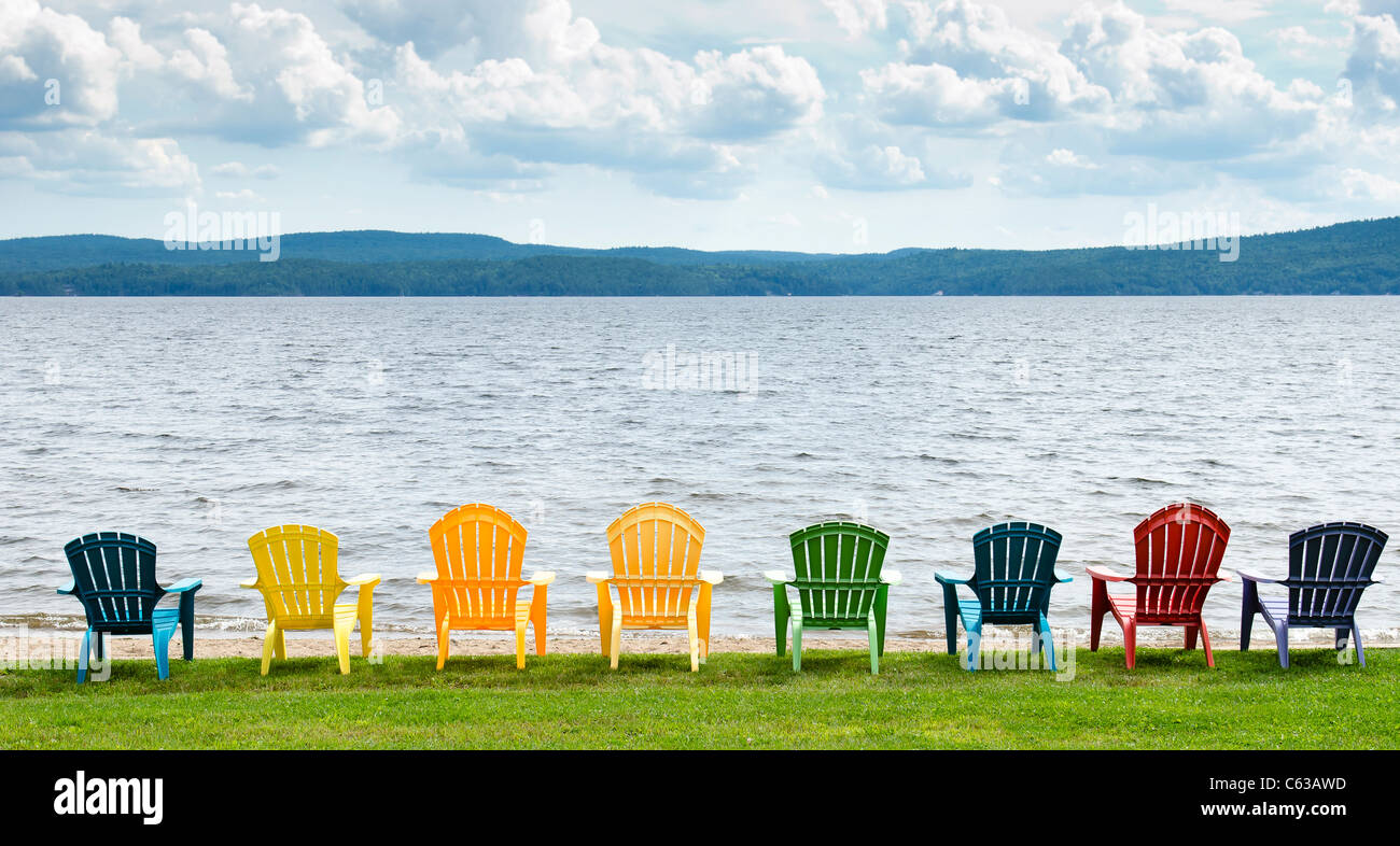 Eight colorful Adirondack chairs lined up on the beach looking out on ...