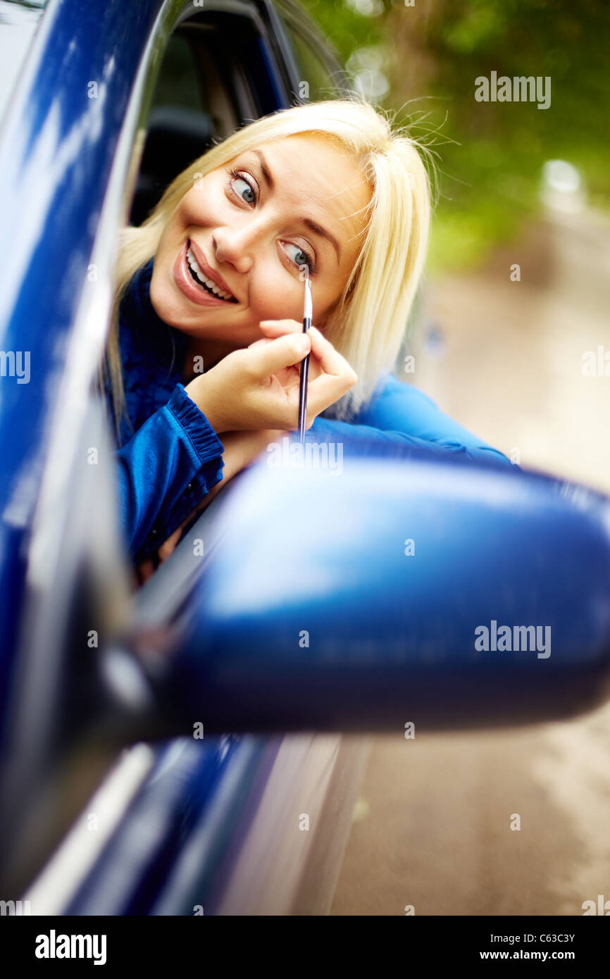 Photo of happy woman looking into car side mirror from car window while ...
