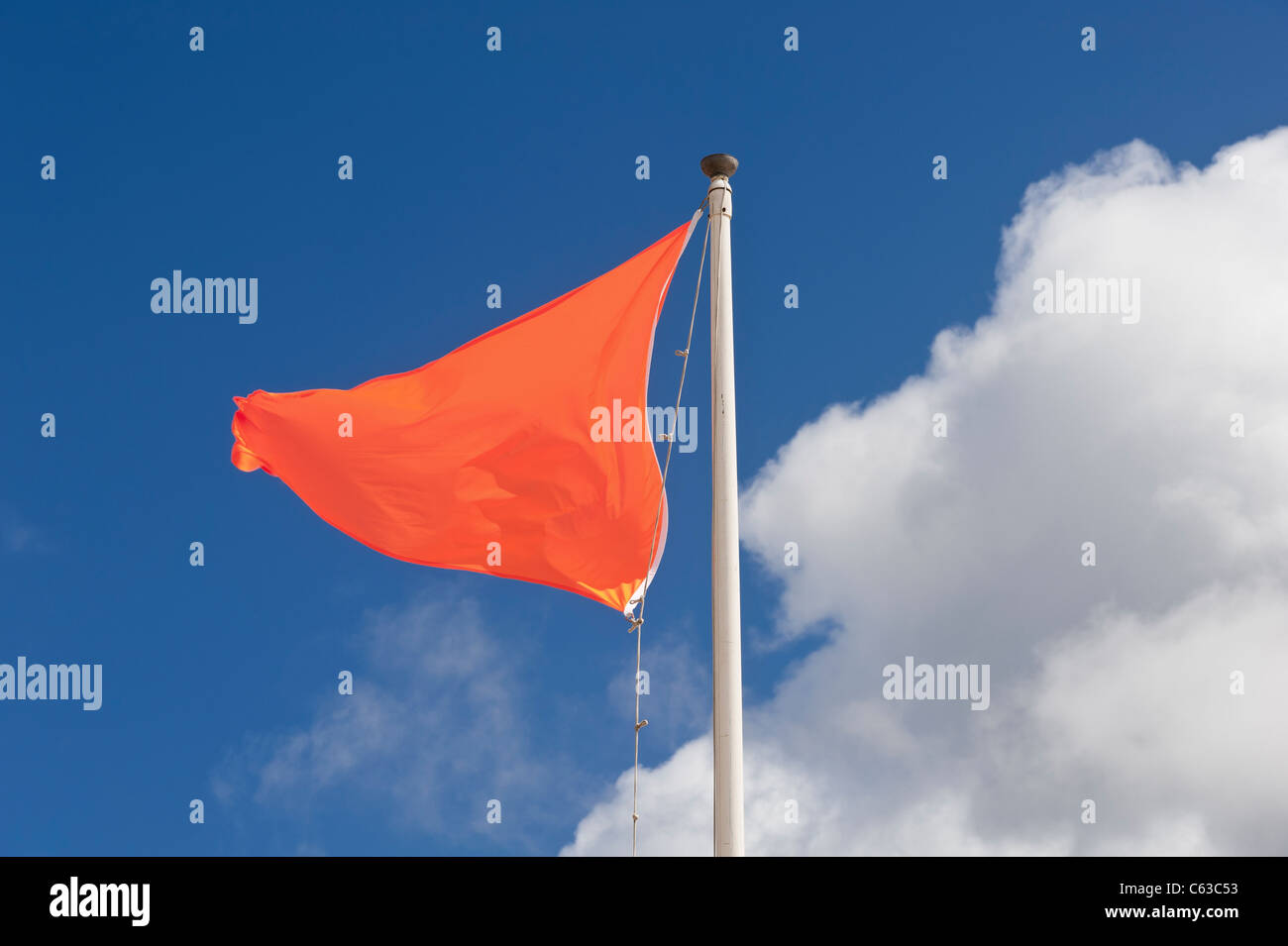 Orange flag flapping flying in the wind Stock Photo - Alamy