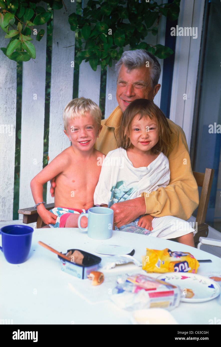 Happy Dad with son and daughter with sleepy morning look over breakfast ...
