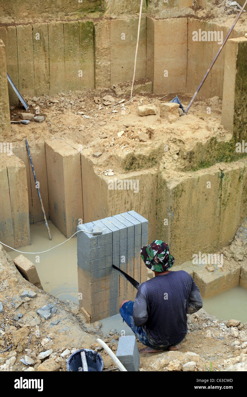Man cutting bricks straight from the ground. Ciracap, West Java ...