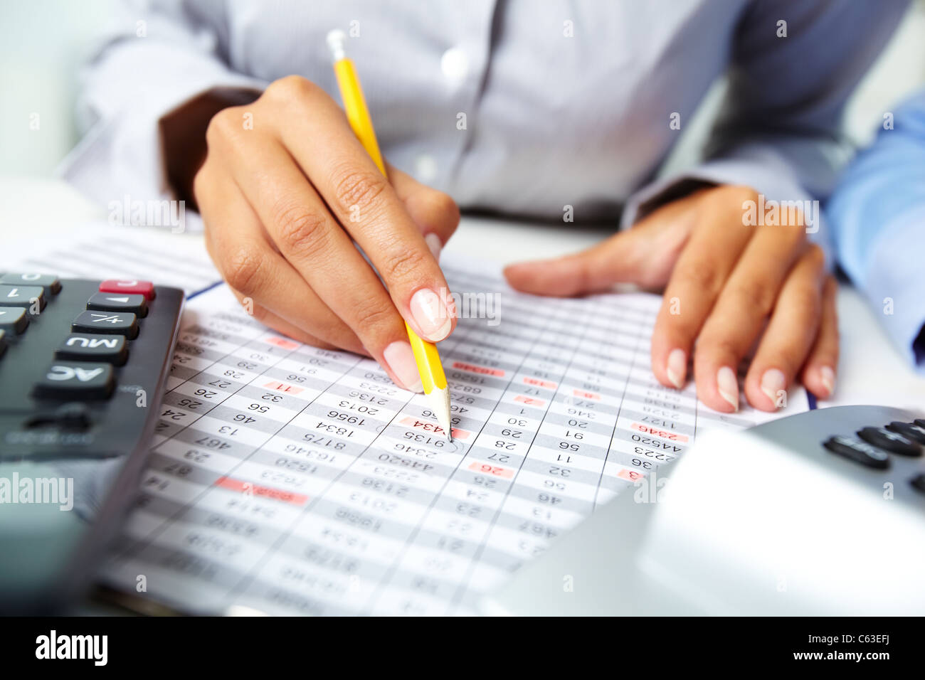 Photo of human hands holding pencil and marking numbers in documents ...
