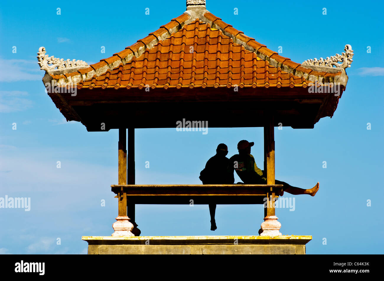 2 silhouetted males sitting in a Balinese bale pavilion at Nusa Dua ...
