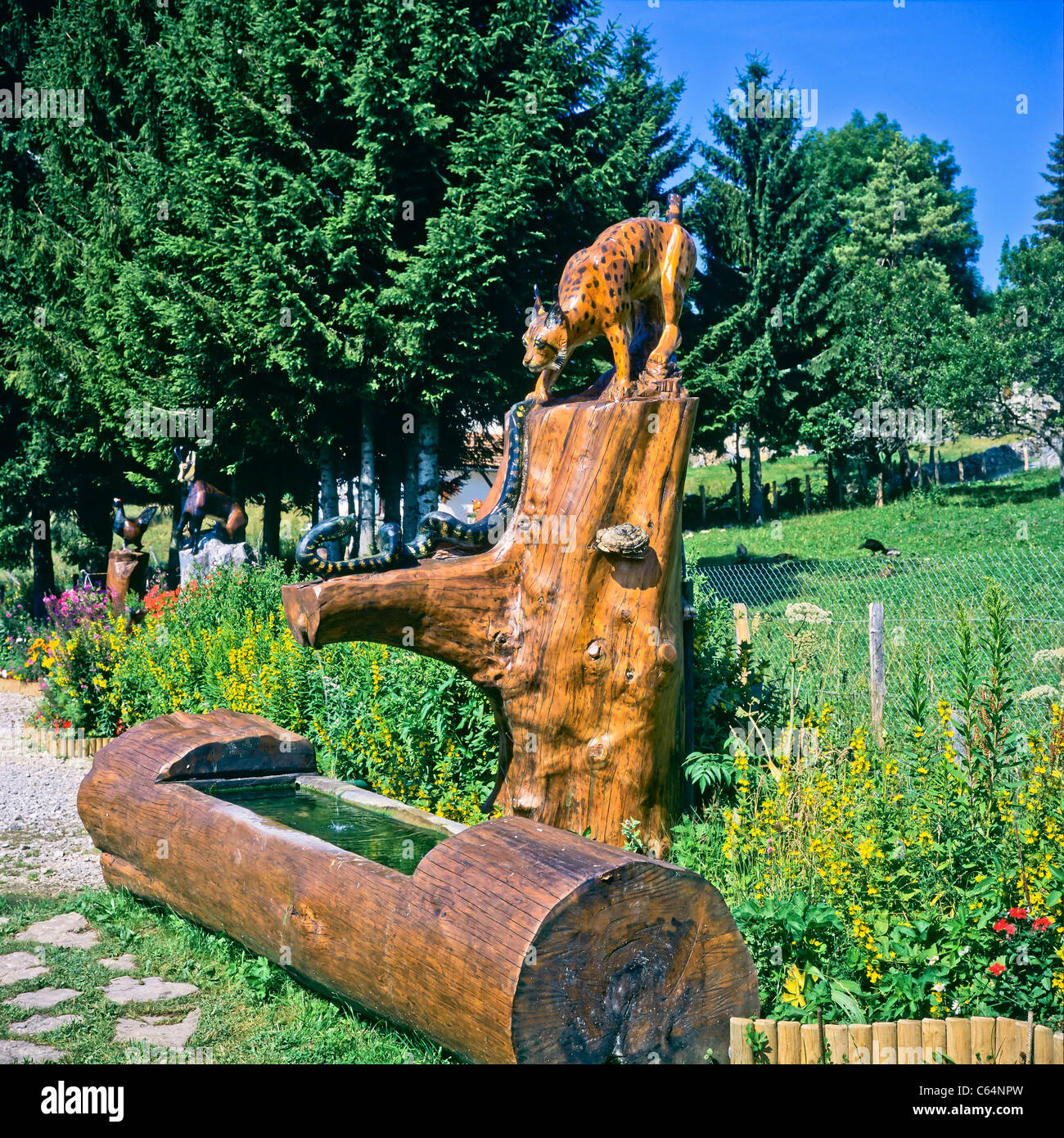 Wooden drinking trough, fountain with wooden carvings of a snake and a ...