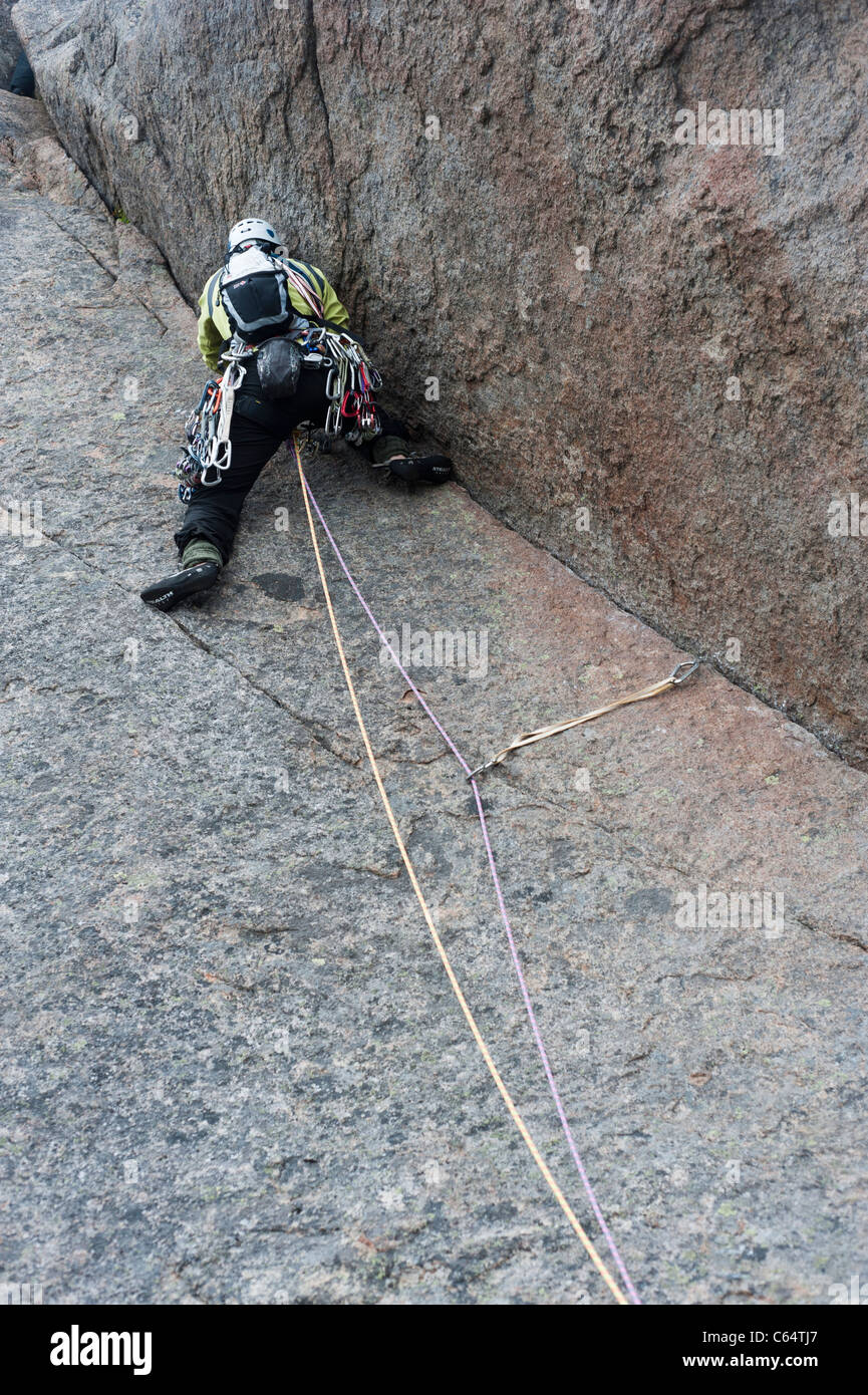 A female rock climber climbing in traditional style in Lofoten Islands ...