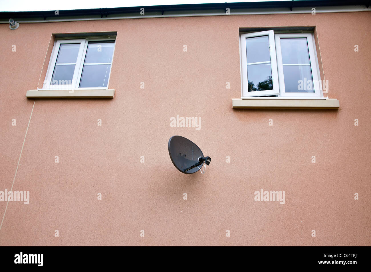 Satellite TV reception aerial (dish) mounted on the wall of a domestic ...