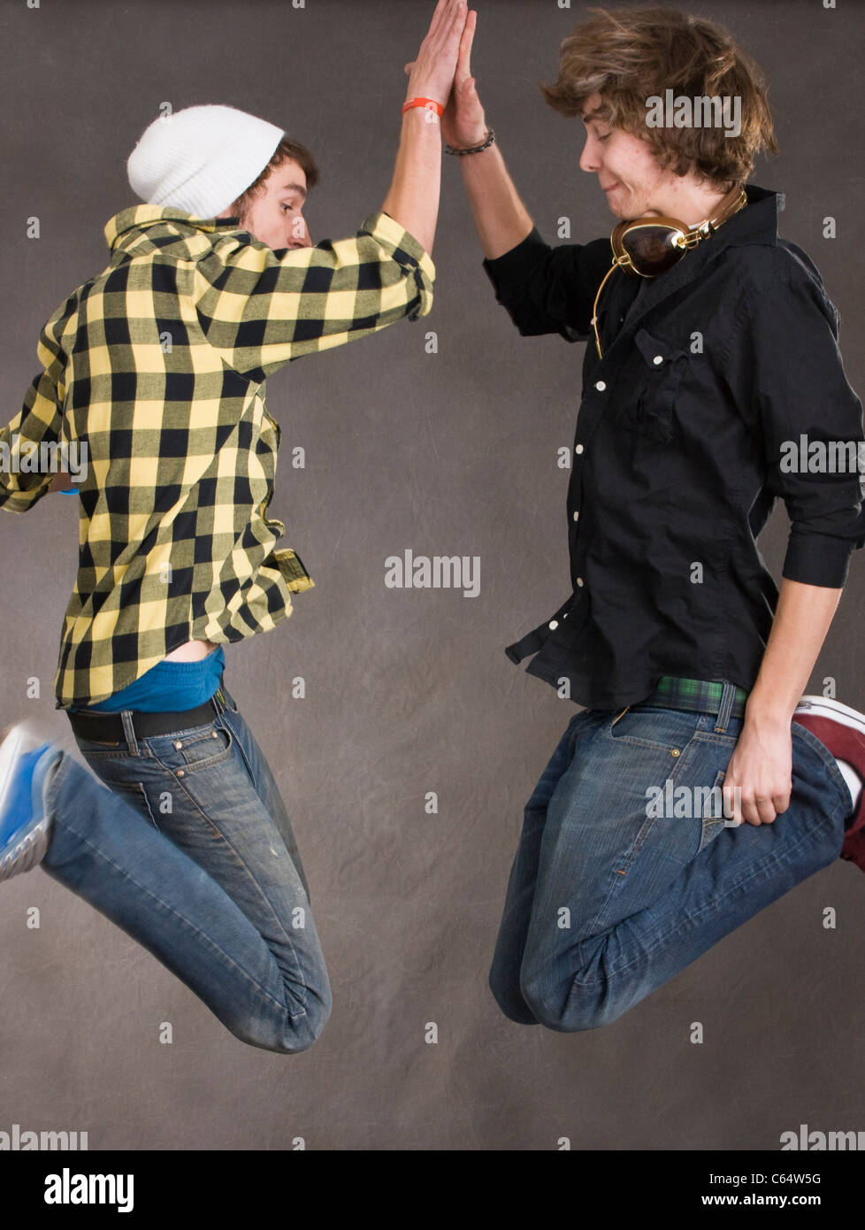 Two young men, friends, jumping for a studio photographic portrait ...