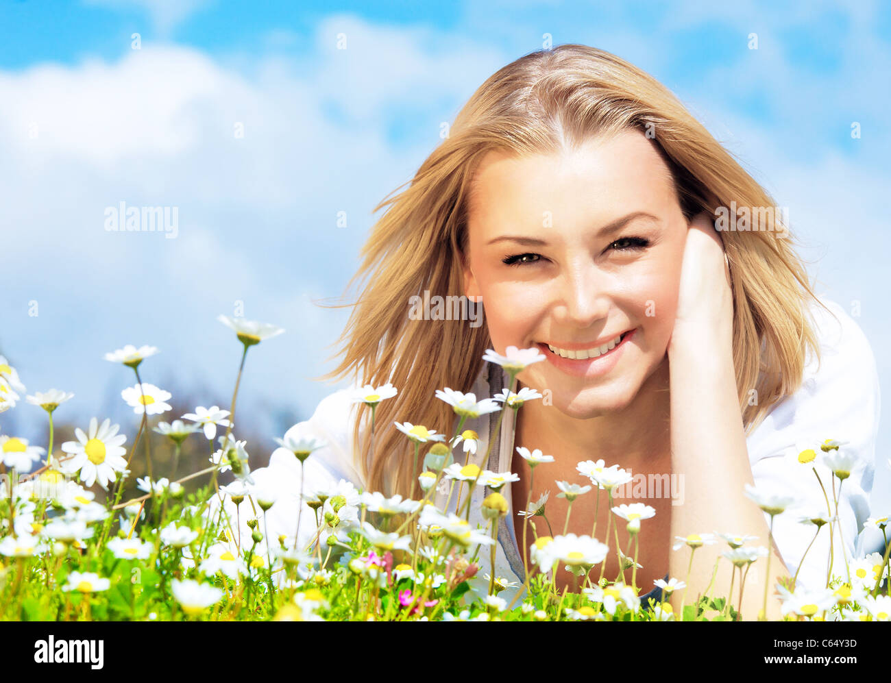 Young beautiful girl laying on the daisy flowers field, outdoor ...