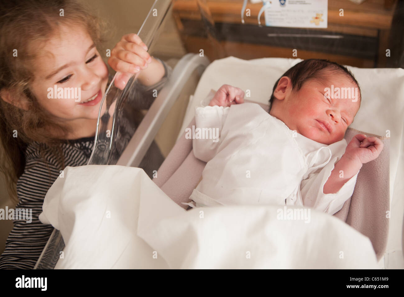 A young girl smiling with happiness as she meets his newborn brother ...