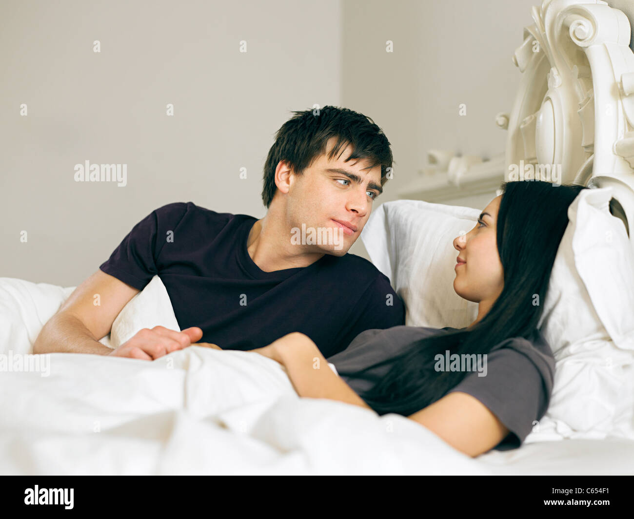 Young couple lying in bed Stock Photo - Alamy