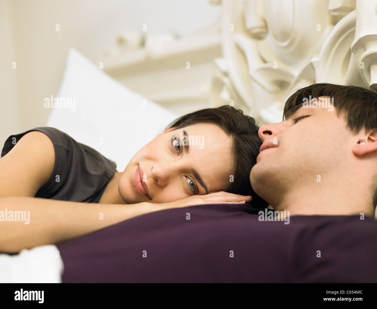 Young couple lying in bed, woman's head on man's shoulder Stock Photo ...