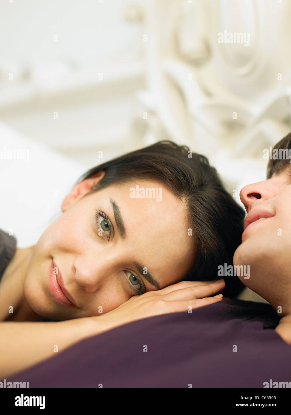 Young couple lying in bed, woman's head on man's shoulder Stock Photo ...