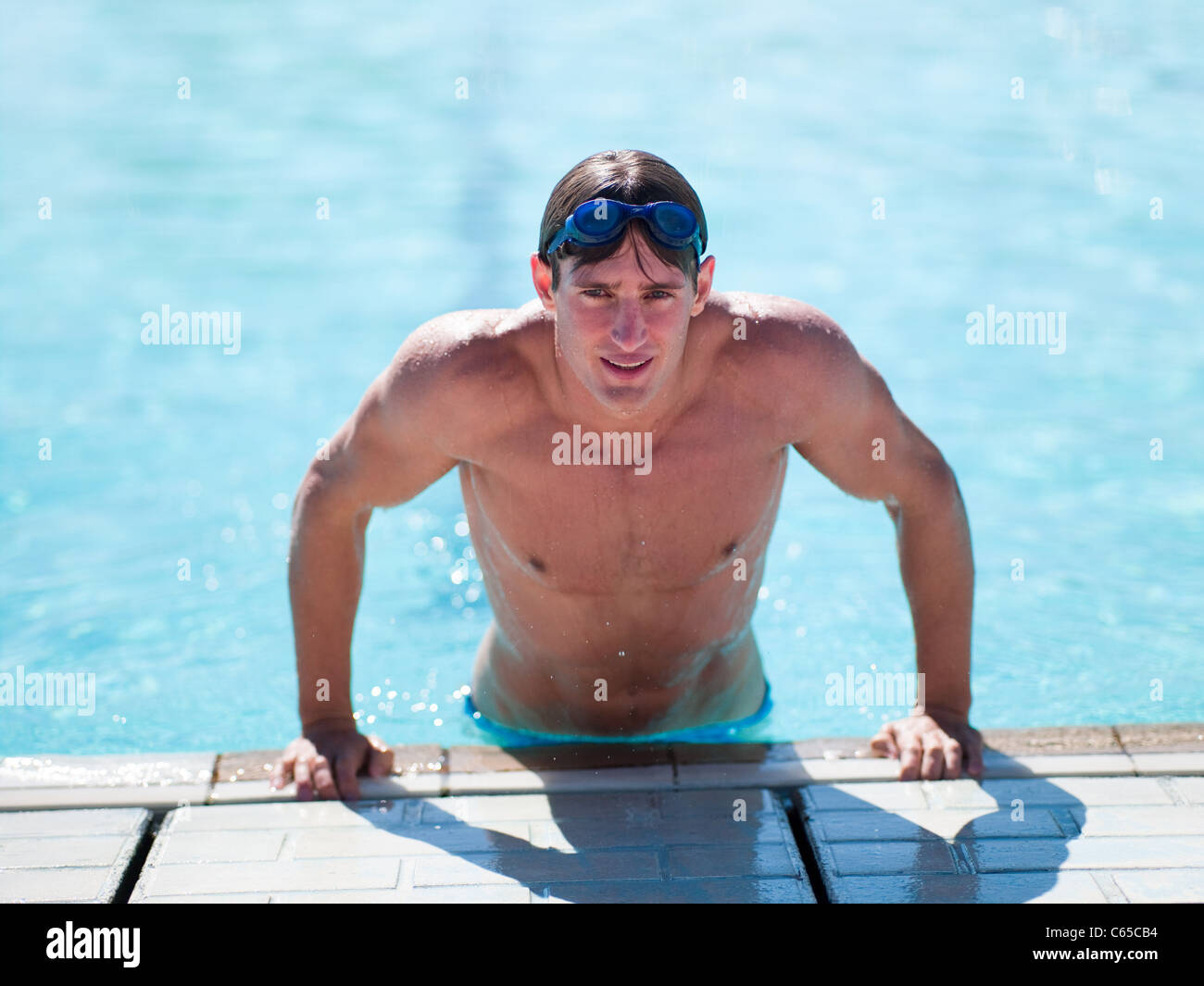 Young man exiting swimming pool Stock Photo - Alamy