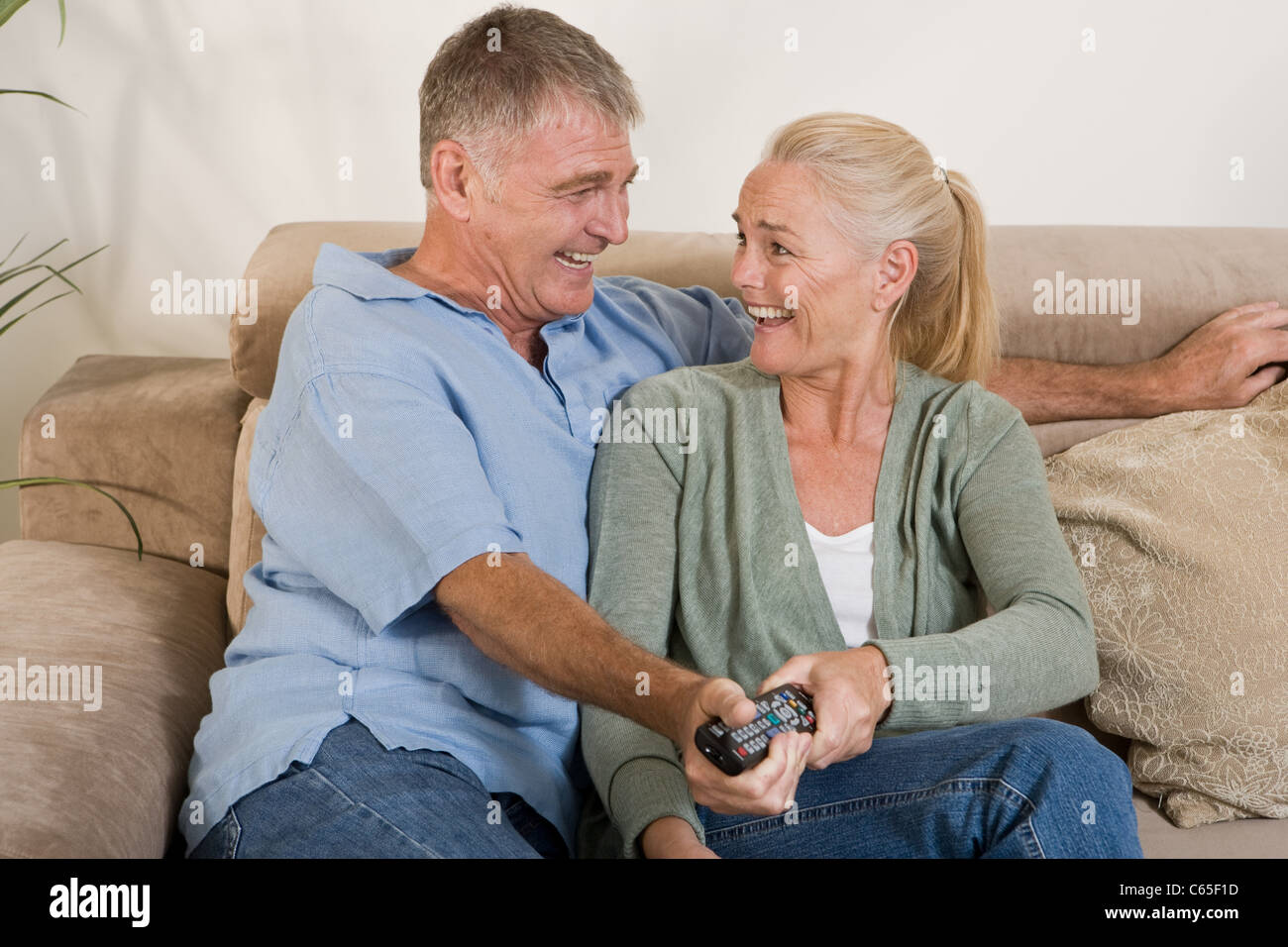 Mature couple both holding a remote control Stock Photo - Alamy