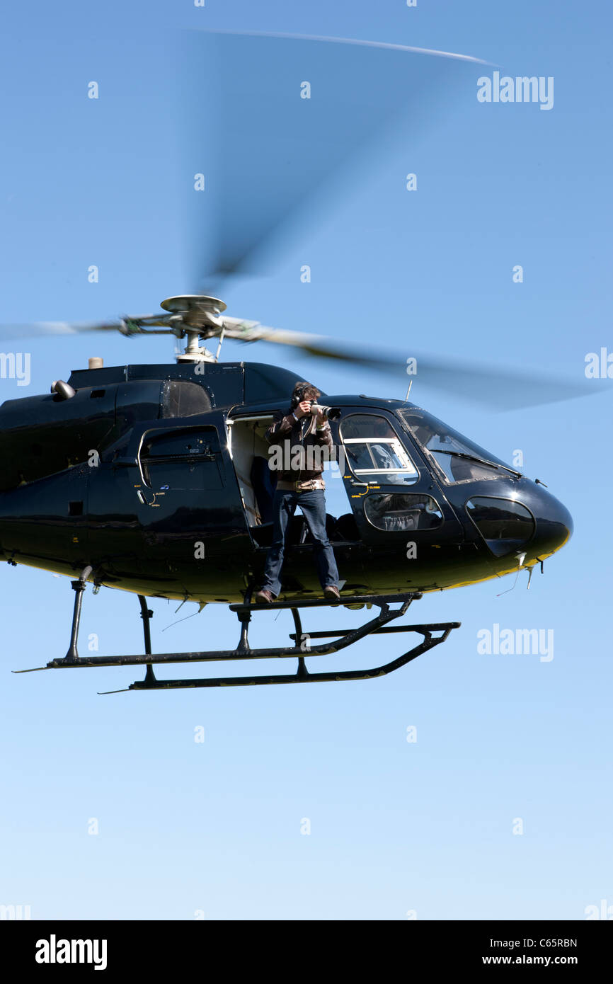 A man hanging from a helicopter taking pictures or doing Aerial ...