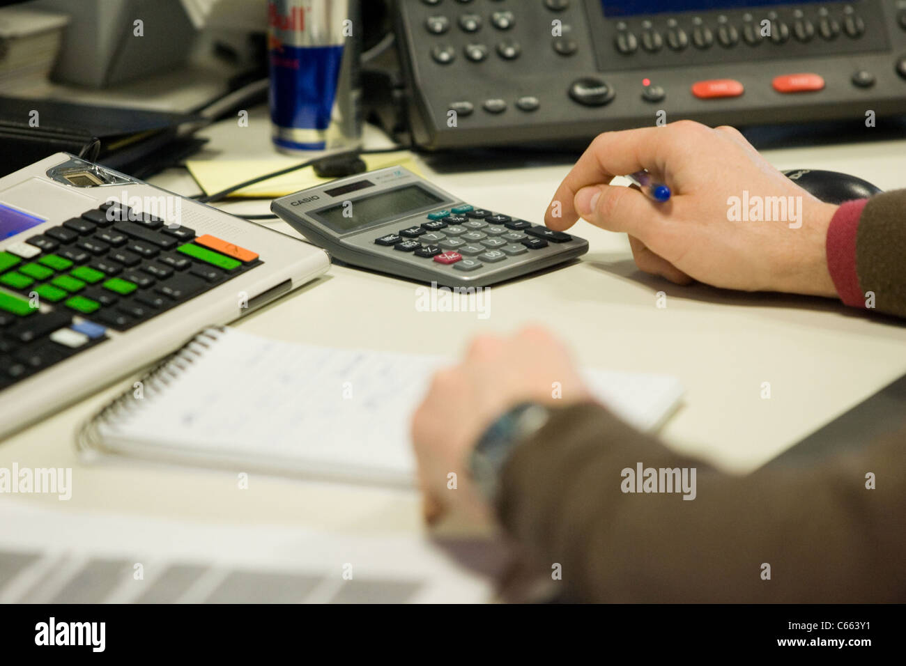 An office worker taps away on his calculator on his desk Stock Photo ...