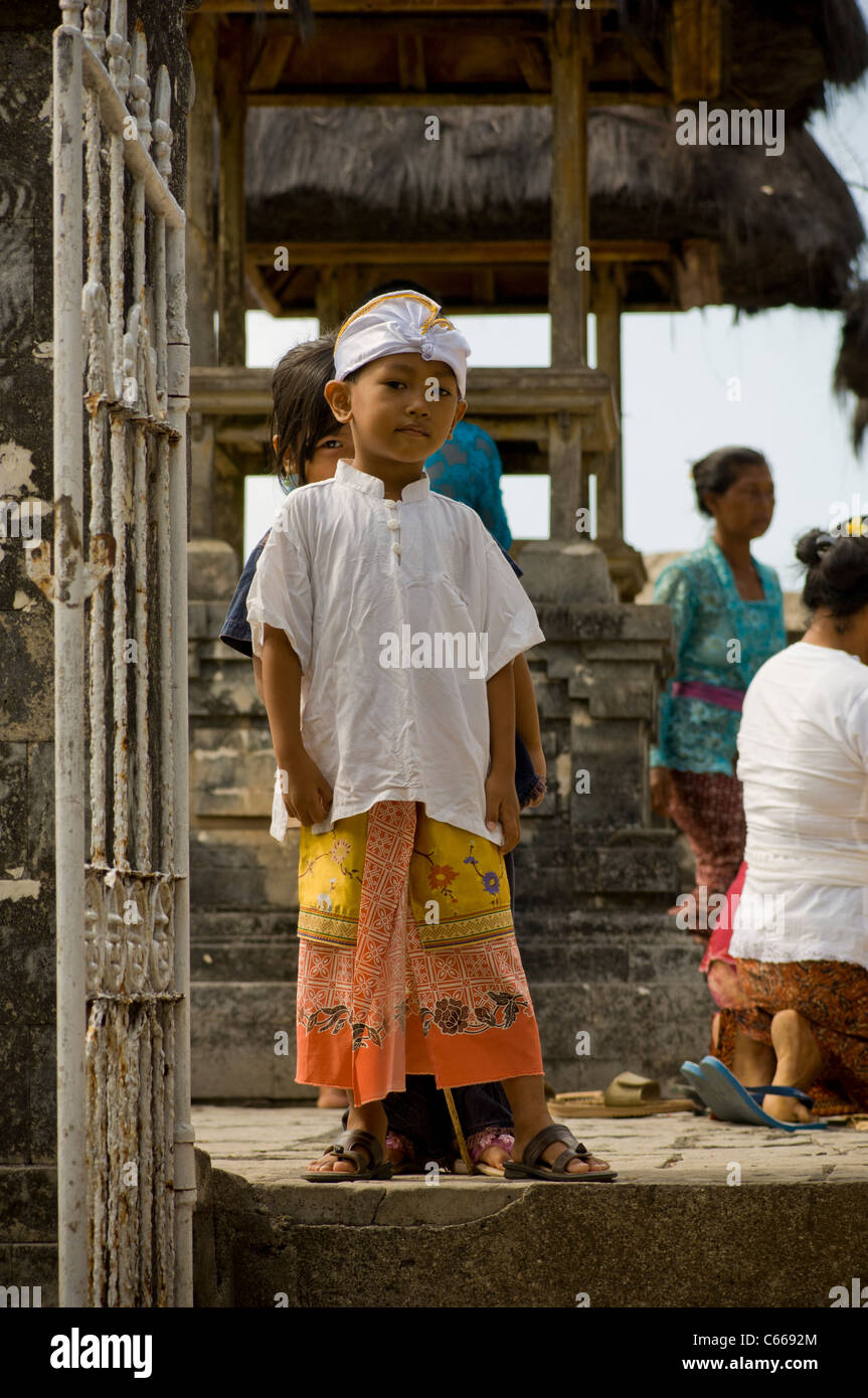 Balinese boy in traditional dress at a Hindu temple, with his sibling ...