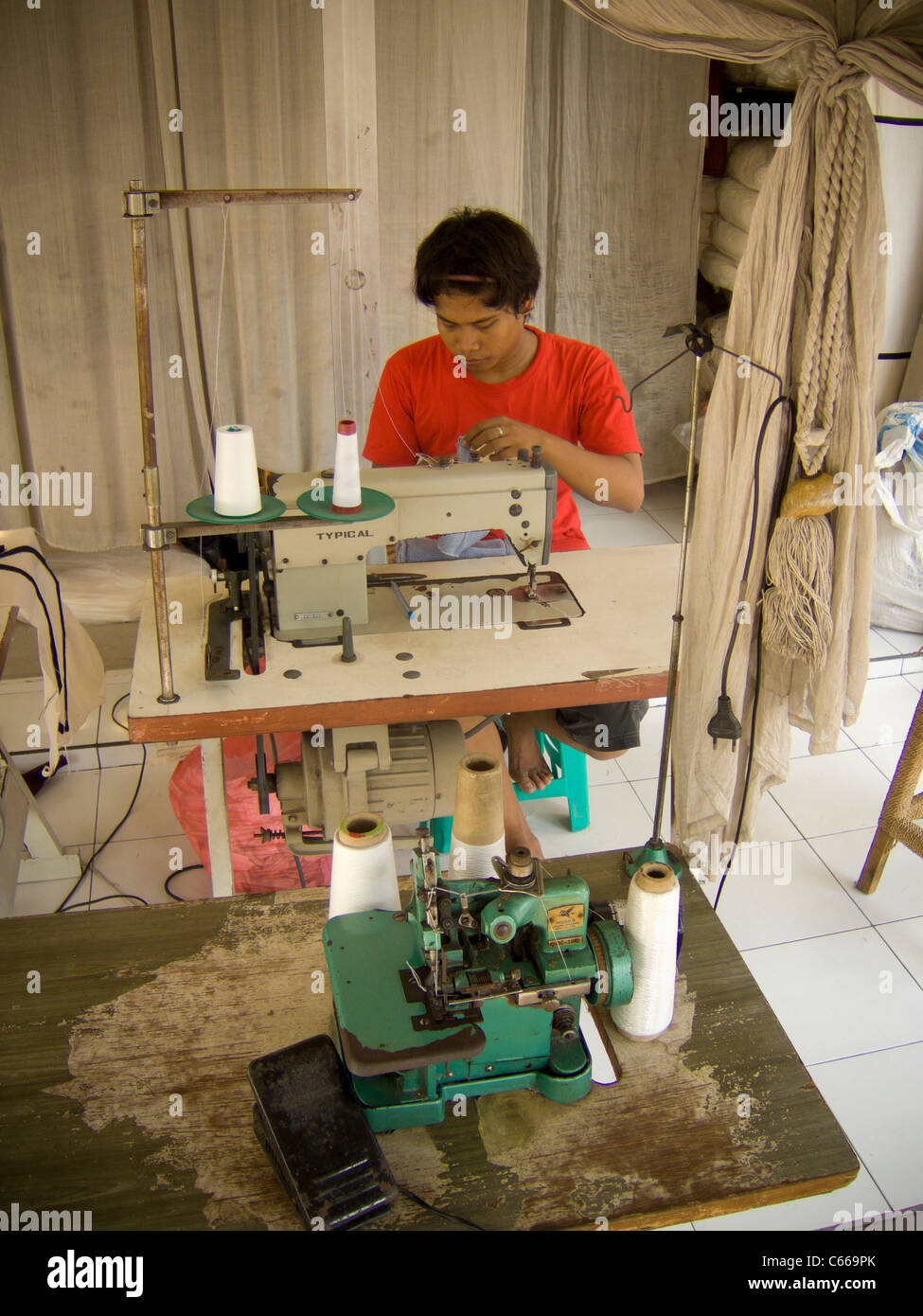 Balinese man working at sewing machine in a roadside tailors shop Stock ...
