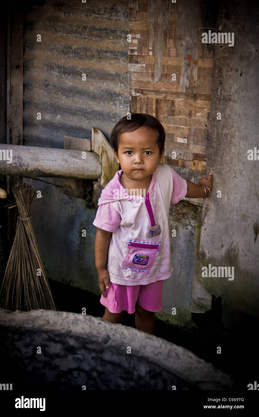 Young Balinese girl standing by the water well in slum area of Bali ...