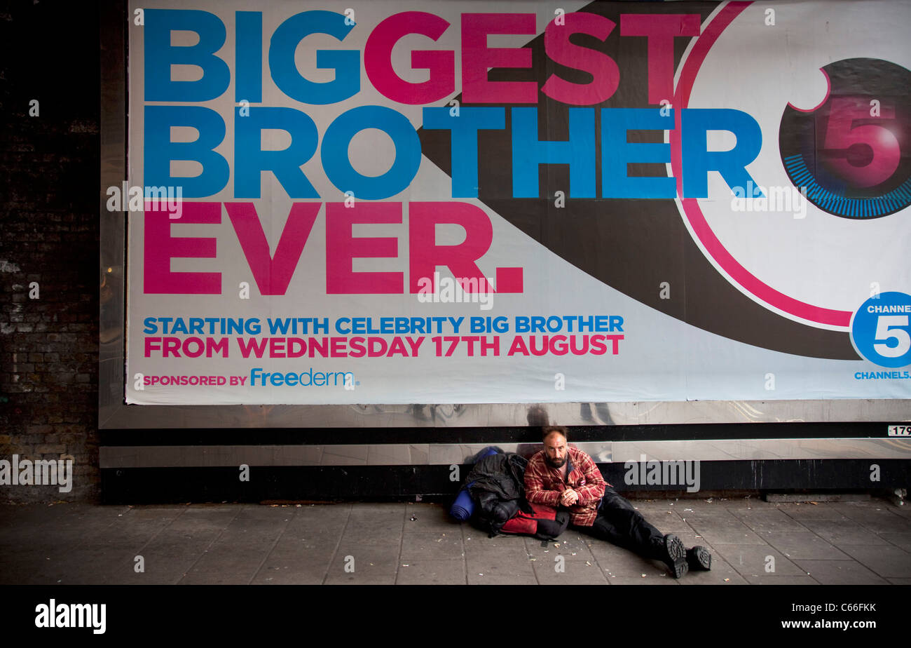 A homeless man lying underneath a billboard advertising poster for the ...
