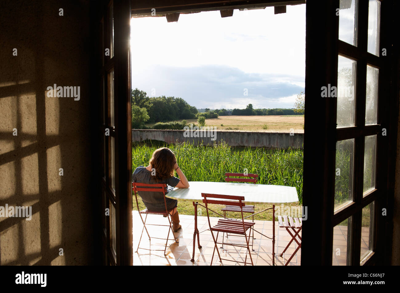 Woman sitting on chair in patio hi-res stock photography and images - Alamy