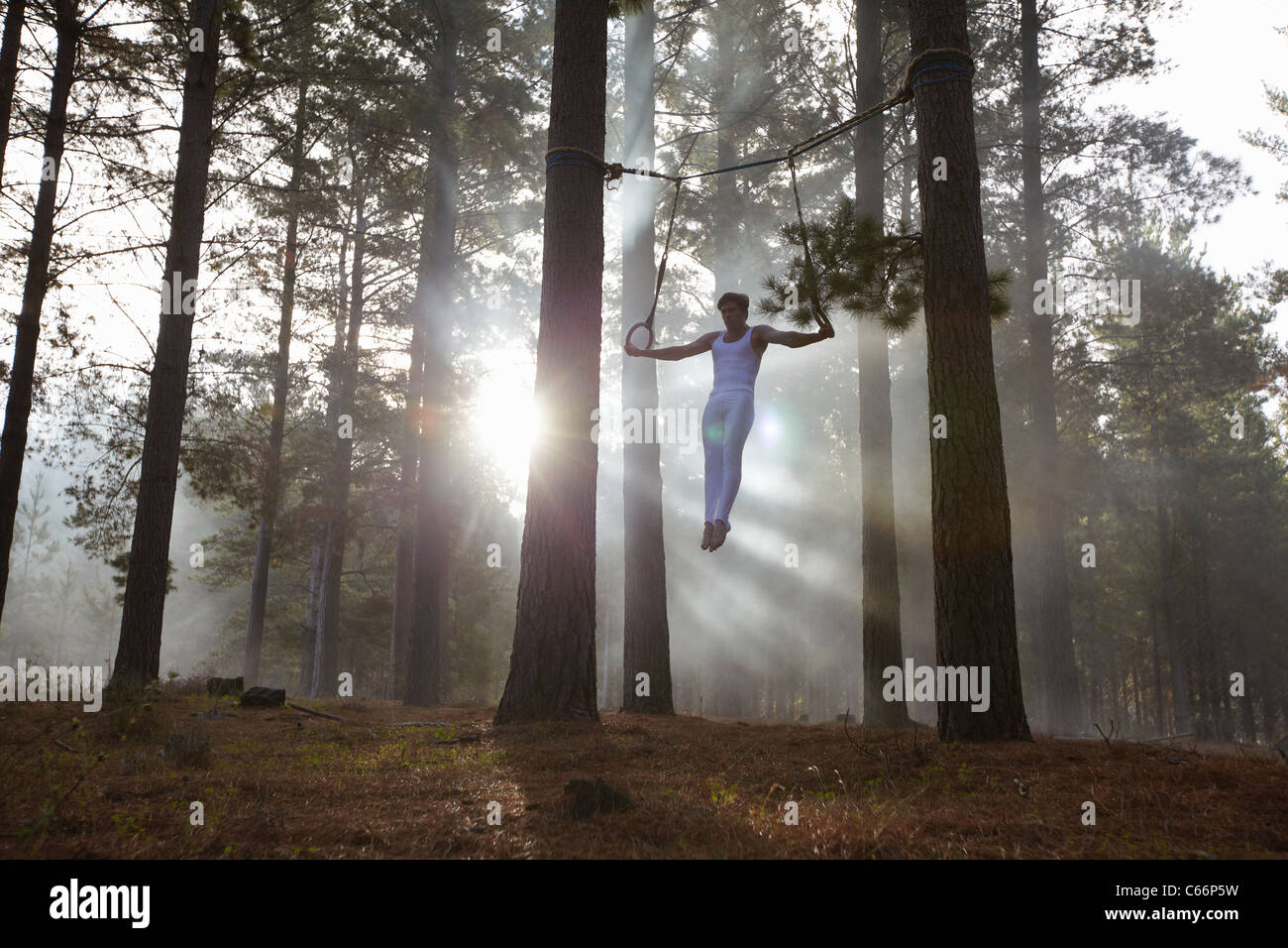 Gymnast using rings in forest Stock Photo - Alamy
