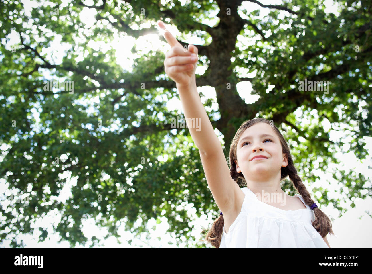 Girl pointing under tree Stock Photo - Alamy