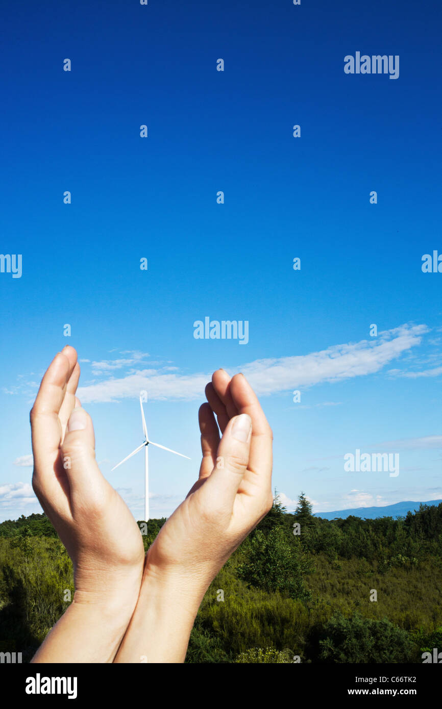 Hands cupped around wind turbine Stock Photo - Alamy