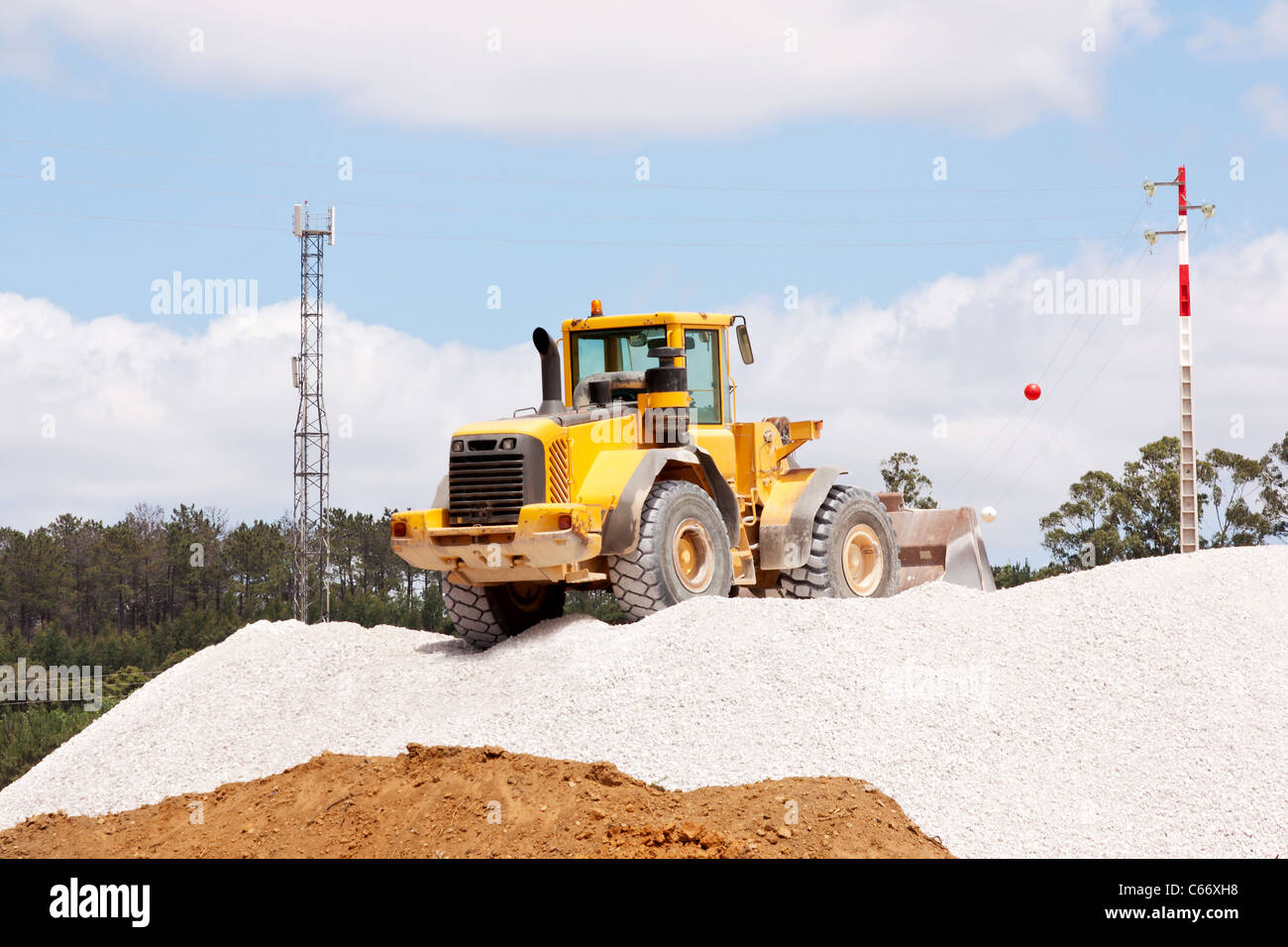 Building bulldozer over a stack of gravel Stock Photo - Alamy