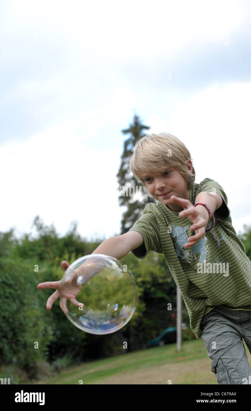 Fair-haired boy with his arms outstretched smiling and running to catch ...