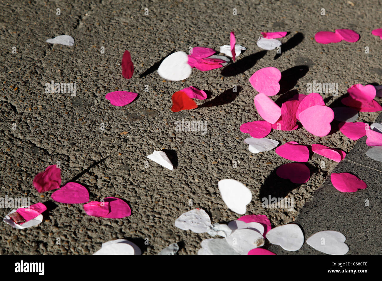 Heart-shaped confetti blown by the wind above asphalt pavement Stock ...