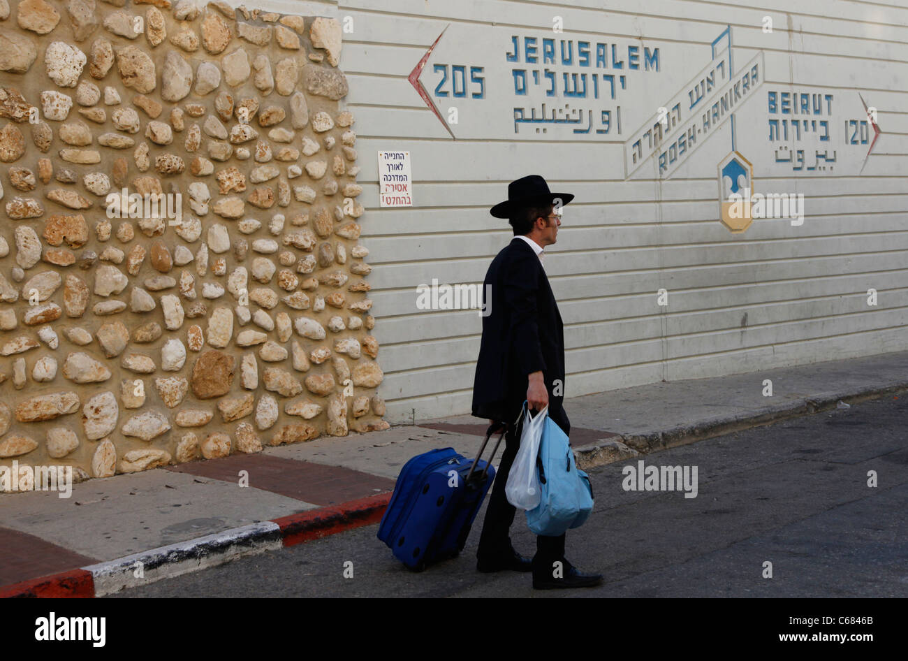 An Israeli Orthodox Jew walks past a sign showing the distance between ...