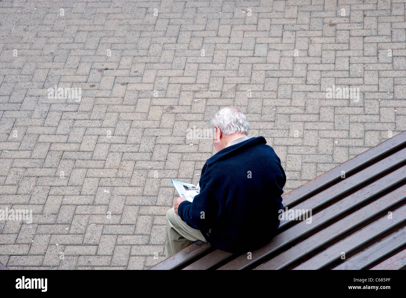 Man sitting on a bench reading (viewed from above Stock Photo - Alamy