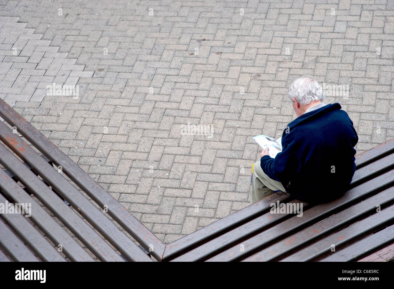 Man sitting on a bench reading (viewed from above Stock Photo - Alamy