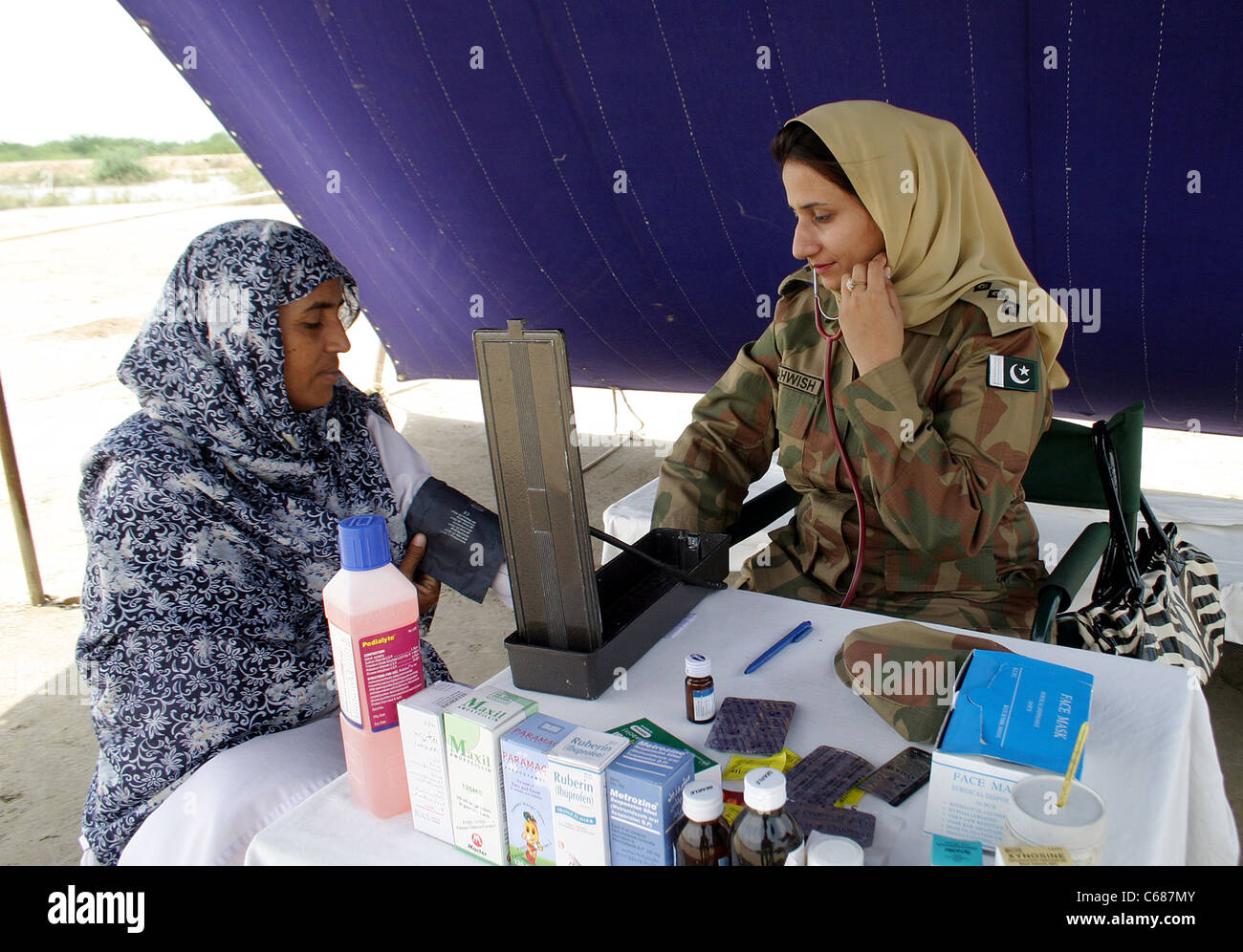 An army doctor examines patient at a flood affectees relief camp ...