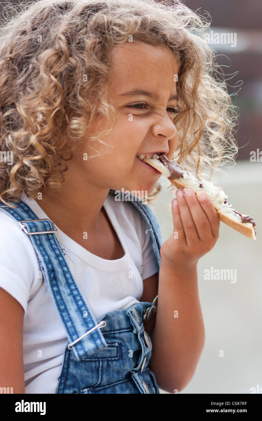 Girl crunching heartily into a slice of bread with chocolate Stock ...