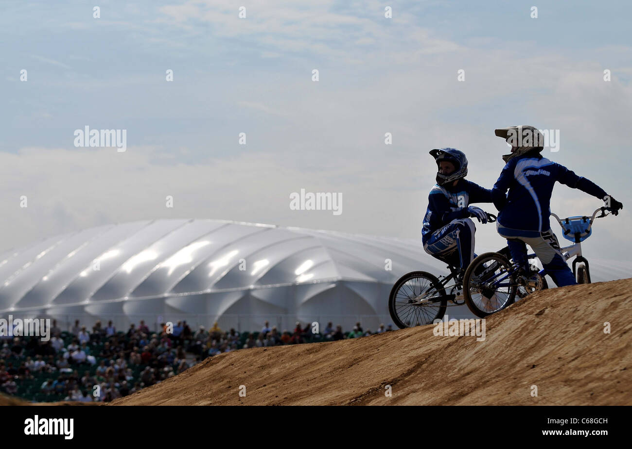 Two riders look back over their shoulder, with the Basketball arena and ...